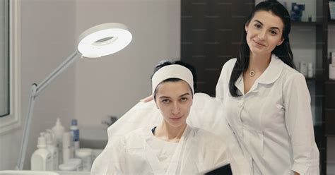 예쁜 여자 미용사는 얼굴 시술을 준비하는 동안 잡지에서 미용의 혁신을 환자에게 보여줍니다 사진 Unsplash의 진료소 이미지