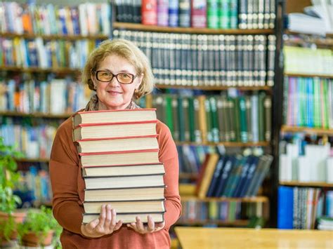 Download Elderly Librarian Holding A Book Wallpaper