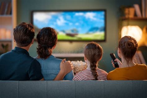 Familia Viendo La Televisión Por La Noche En Casa Imagen De Archivo