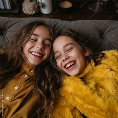 Candid Moment Between Teenage Sisters Laughter And Bonding On A Couch