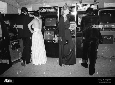 Wealthy Middle Class Young Adults Playing With Space Invaders Machines