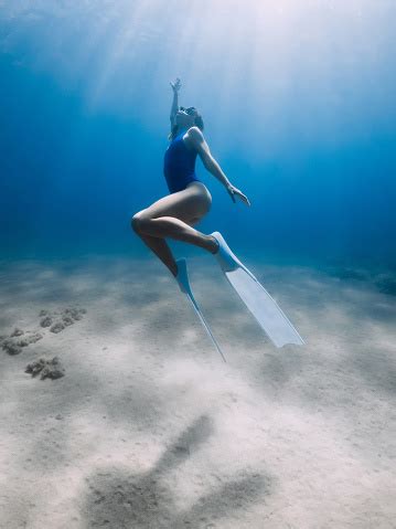 Lady Freediver With Fins Posing And Glides Underwater In Ocean With