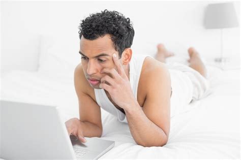 Casual Joven Usando La Computadora Portátil En La Cama Foto Premium