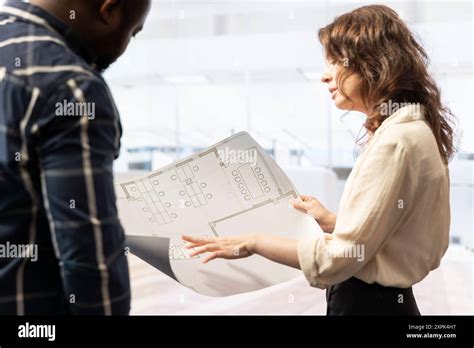 Realtor And Business Entrepreneur Examining Blueprints For A High Class Workspace Rental