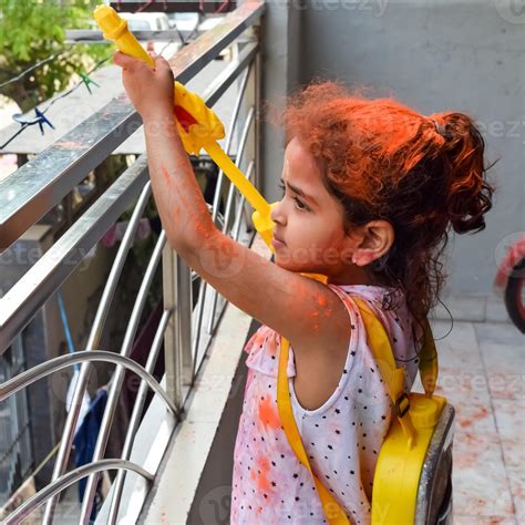Sweet Little Indian Girl Playing Colours On Holi Festival Holding