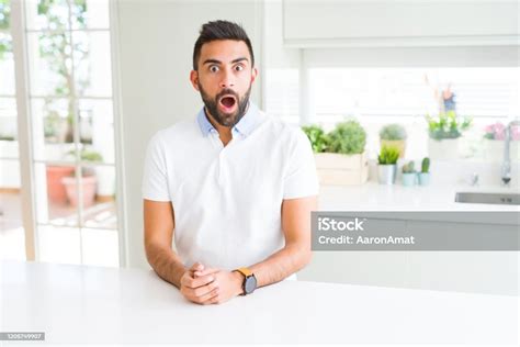 집에서 잘 생긴 히스패닉 남자 캐주얼 흰색 티셔츠를 두려워 하 고 깜짝 표정 두려움과 흥분 된 얼굴충격 T 셔츠에 대한 스톡 사진 및 기타 이미지 Istock