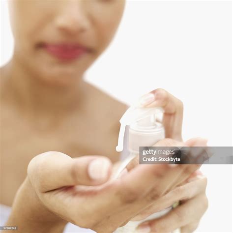 Closeup Of A Young Woman Squirting Lotion Into Her Hand High Res Stock
