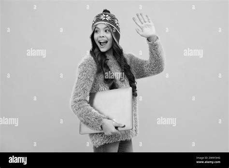 Back To School Teenager Schoolgirl With Warm Hat And Sweater Hold Laptop On Yellow Isolated
