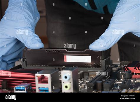 Close Up Of Man Hands With Gloves Installing Ram DDR Memory Module In Slot On Motherboard Stock