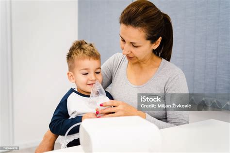 여자 어머니는 증기 증기 흡입기 분무기 마스크 흡입을 사용하여 그녀의 작은 아들 소년 아이를 집 이나 병원 의료 절차 약치료 치료 천식 폐렴 기관지염 기침 아픈 2 3 살에