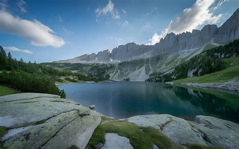 Photograph Of A Serene Deep Blue Alpine Lake Fringed By Forest And