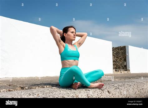 Sporty Woman Sitting With Her Hands Behind Her Head Stretching Outside