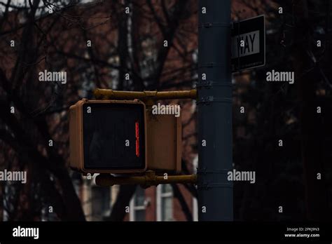 A Traffic Signal Is Mounted On A Metal Pole Beside A Brick Facade Of A