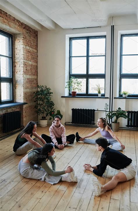 Group Of Active Teens Sitting On The Floor And Practicing Stretching