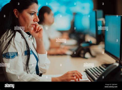 Female Security Guard Operator Talking On The Phone While Working At Workstation With Multiple