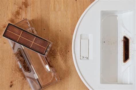 Premium Photo Cleaning The Filter Of The Vacuum Robot Cleaner From Dirt Closeup