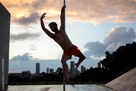 Muscular Male Pole Dancer Holding A Pose On A Pole Set Outdoors