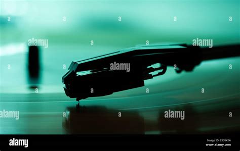 A Close Up Record Player Needle On A Vinyl Record With A Teal