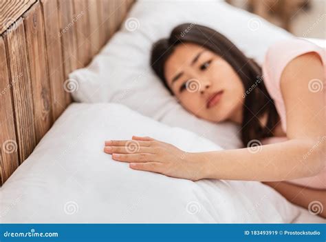 Asian Woman Touching Pillow Lying In Bed Alone After Breakup Stock
