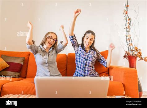 Two Very Happy Girl Cheering With Hands Up Looking At Laptop Screen