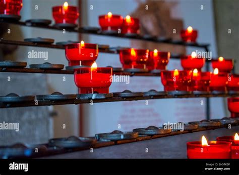 Burning Red Prayer Candles Inside A Catholic Church On A Candle Rack