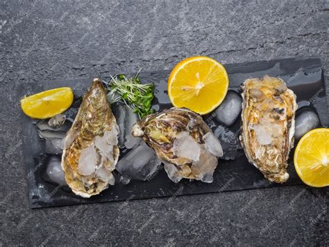 Premium Photo Fresh Raw Oysters On Ice With Lemon Slices On Stone