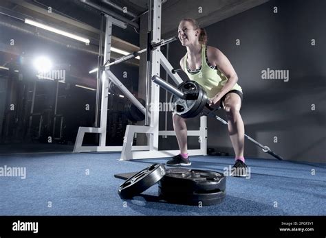 Young Woman Doing Bent Over Row Exercising With Long Barbell In The Gym