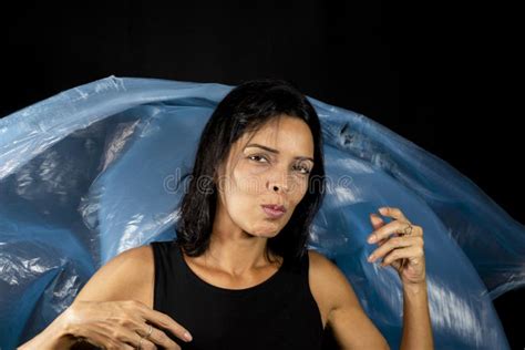 Portrait Of Woman With Clear Blue Plastic Behind Her Body Against Black