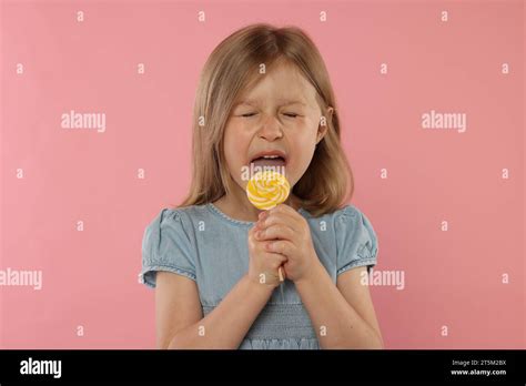 Cute Girl Licking Lollipop On Pink Background Stock Photo Alamy