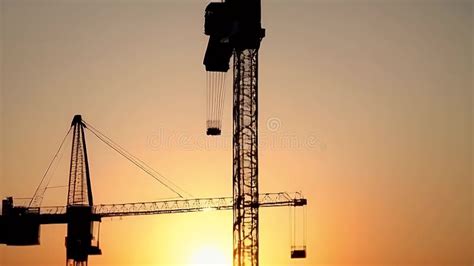 Dramatic Silhouette Of Construction Cranes Over Golden Sky During