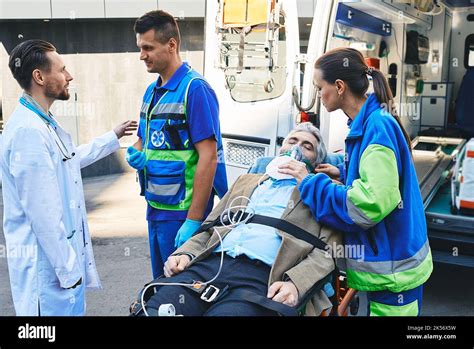 Doctor And Paramedics Checking Health Of Mature Male With Breathing