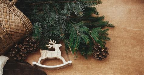 제로 웨이스트 크리스마스 소박한 순록 장난감 장갑 전나무 가지가 있는 바구니 소박한 나무 배경에 원뿔 겨울 휴가 준비 느린 생활 계절 인사말 공간을 복사합니다