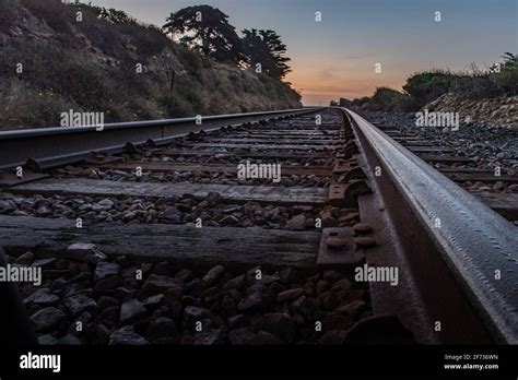 parallel train tracks lead up to the horizon as dawn begins to light