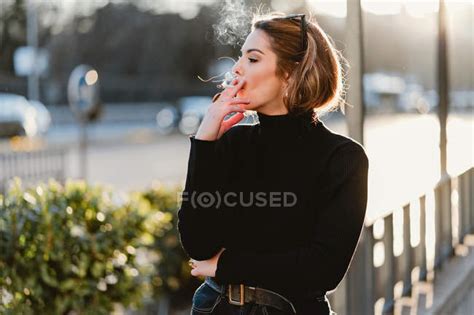 Pretty Woman Smoking Cigarette On Sunny Street — Looking Away