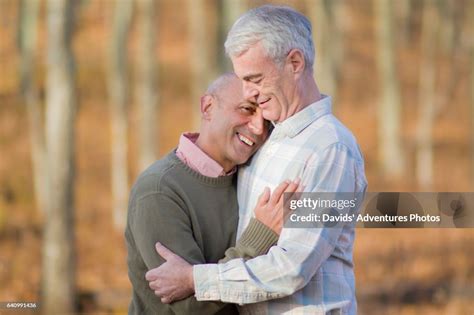 Mature Gay Couple Affectionately Embracing In Wooded Area In An
