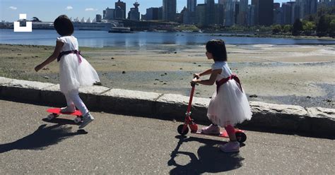 드레스를 입은 두 어린 소녀가 물가에서 스쿠터를 타고 있다 사진 Unsplash의 무료 不列颠哥伦比亚省加拿大 이미지