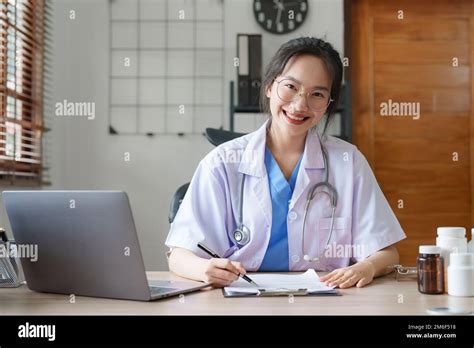 Portrait Of Female Asian Doctor Working With Patient Document In Her Office At Clinic Stock