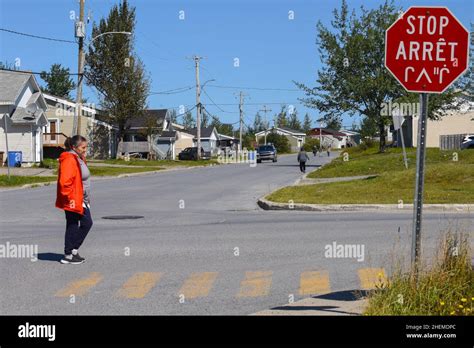 Indigenous Cree Woman Walking In Front Of Stop Sign In Three Languages