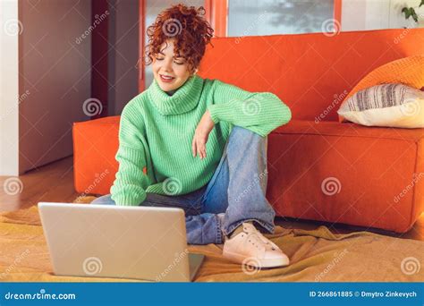 Ginger Girl In Green Sweater Sitting On The Floor At The Laptop Stock