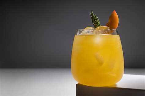 얼음 녹색 로즈마리 복숭아 슬라이스가 있는 차가운 오렌지 과일 음료는 우아한 미니멀한 다크 화이트와 그레이 추상적인 인테리어로 단단한 빛과 그림자를 드리우고 있습니다 감귤류