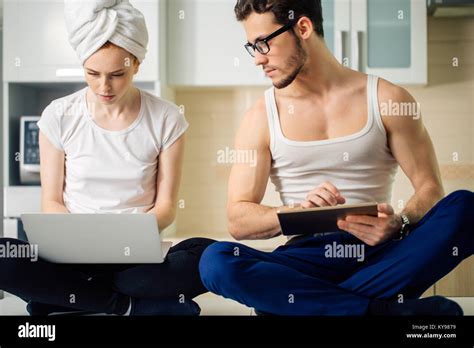 Man Holding Tablet Spying His Girlfriends Laptop While She Is Typing