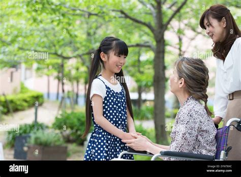 Mother And Daughter Accompanying Wheelchair Bound Grandmother Stock