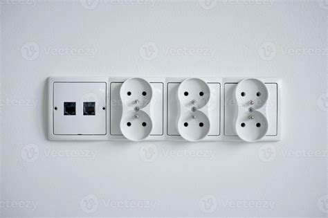 Close Up Of White Electrical Sockets And Ethernet Ports On White Wall