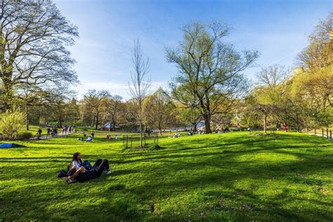 People Relaxing On Green Grass In Central Park On Sunny Spring Day With