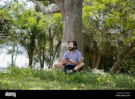 Young Man At A Park On A Beautiful Sunny Day With Mobile Phone Mobile