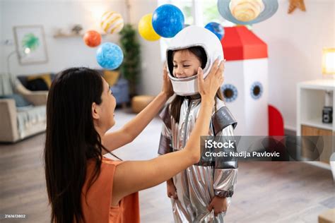Girl In A Space Suit Playing With Her Mom At Home Imagining Space