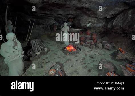 A Cave Interior With Lifesized Statues Flickering Fires And Artifacts