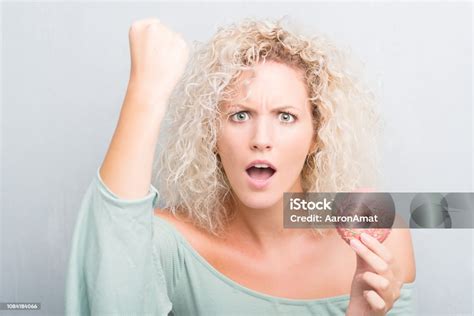 그런 지 그레이 통해 젊은 금발 여자 배경 화가 핑크 도넛 먹고 미친과 제기 손으로 소리 분노와 좌절 외치고 분노 개념 감정에