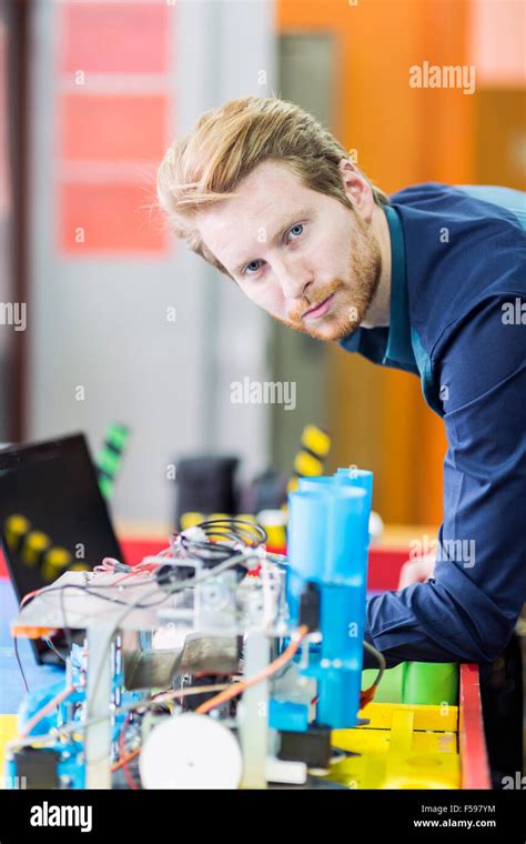 Male Electrical Engineer Programming A Robot During Robotics Class