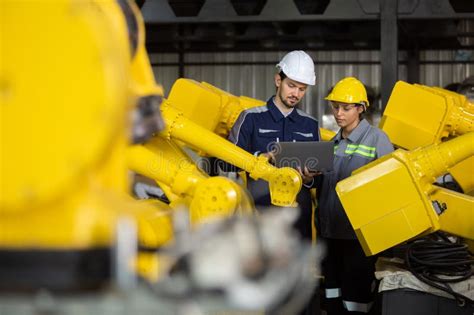 Engineers Working Robot Assembly Industry Plant In Factory Using Laptop